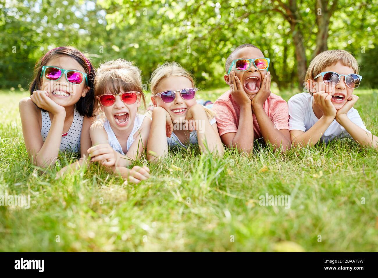 Multicultural group of children lying in the garden laughing with ...