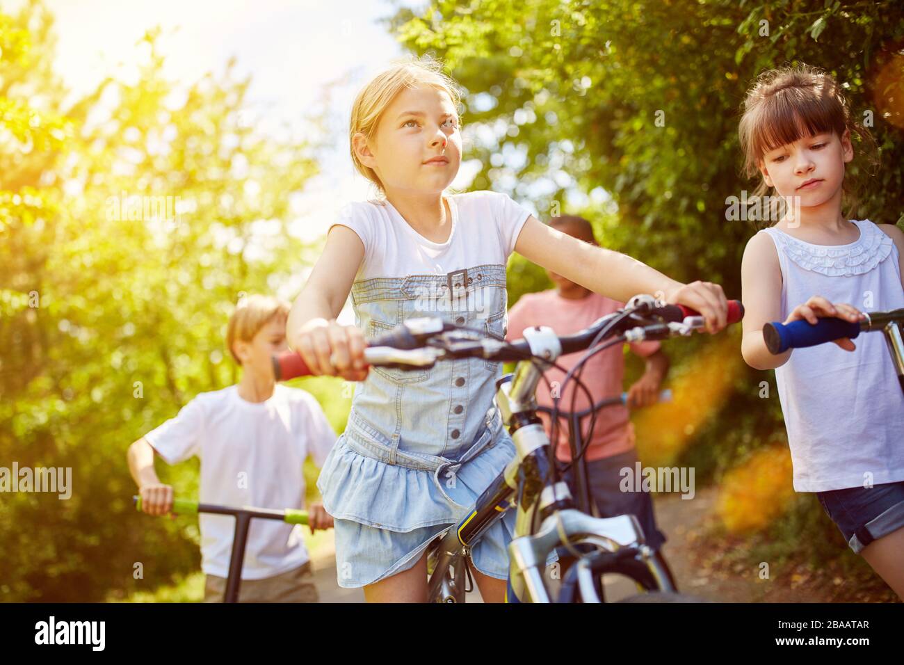 Children ride together on bicycles and scooters in summer Stock Photo ...