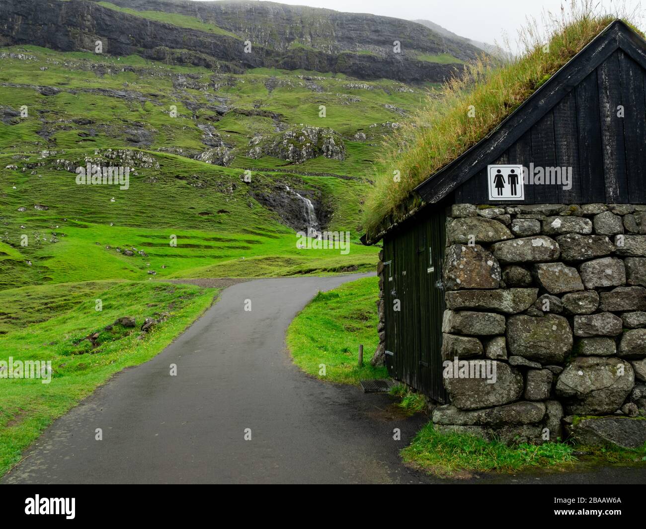 Faroe Islands. Saksun. Road and building of toilets with grass roof ...