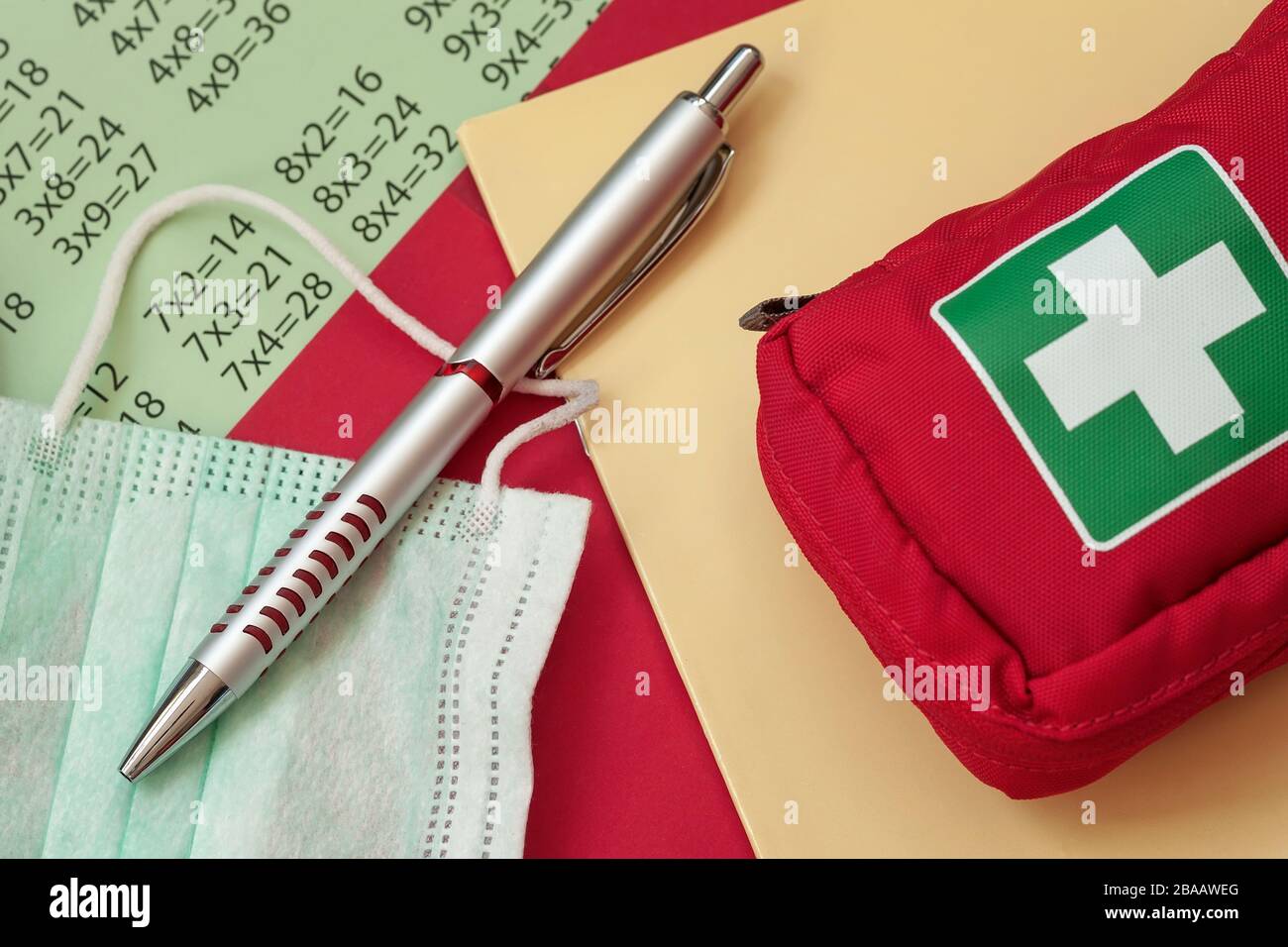 Pen, medical mask and first aid kit on a school notebook. Disease ...