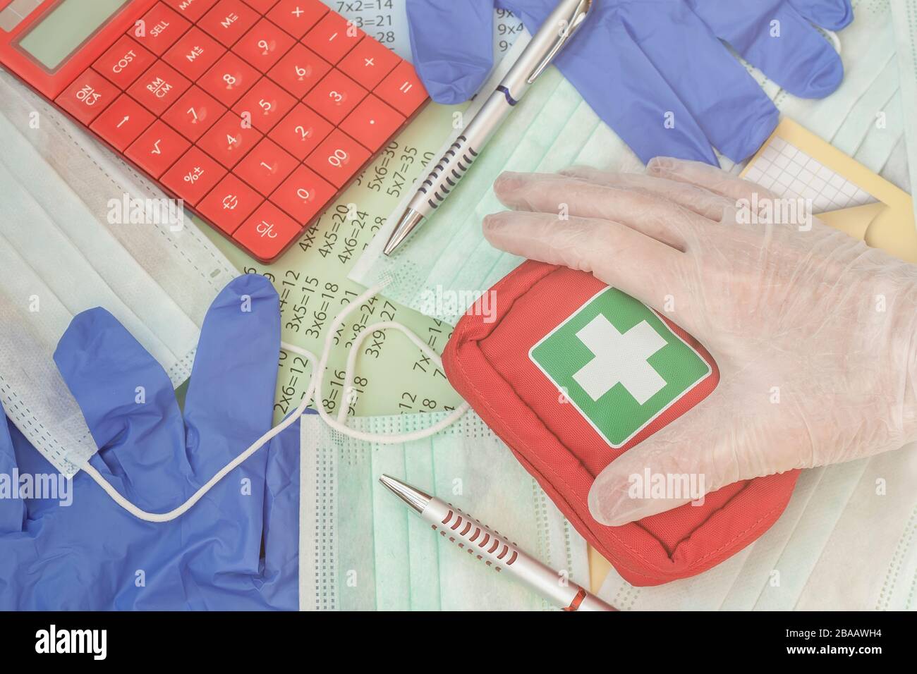 Hand in a medical glove with first aid kit, pens, calculator, medical ...