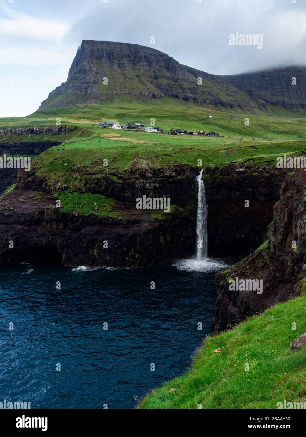 Faroe Islands, famous Mulafossur Waterfall, its water falling into the ...