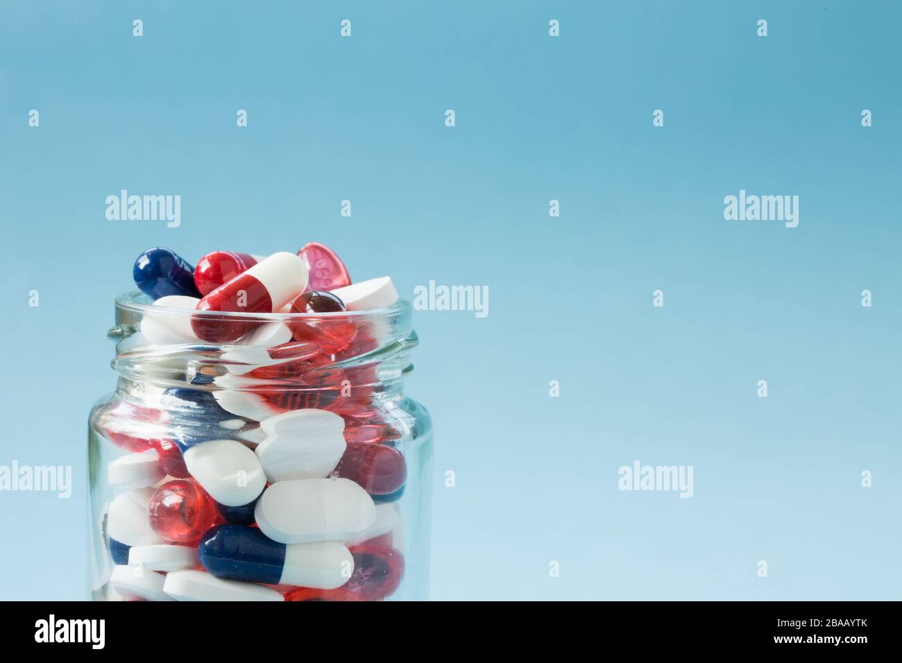 A medicine concept of a jar full of drugs, tablets and pills on a blue ...
