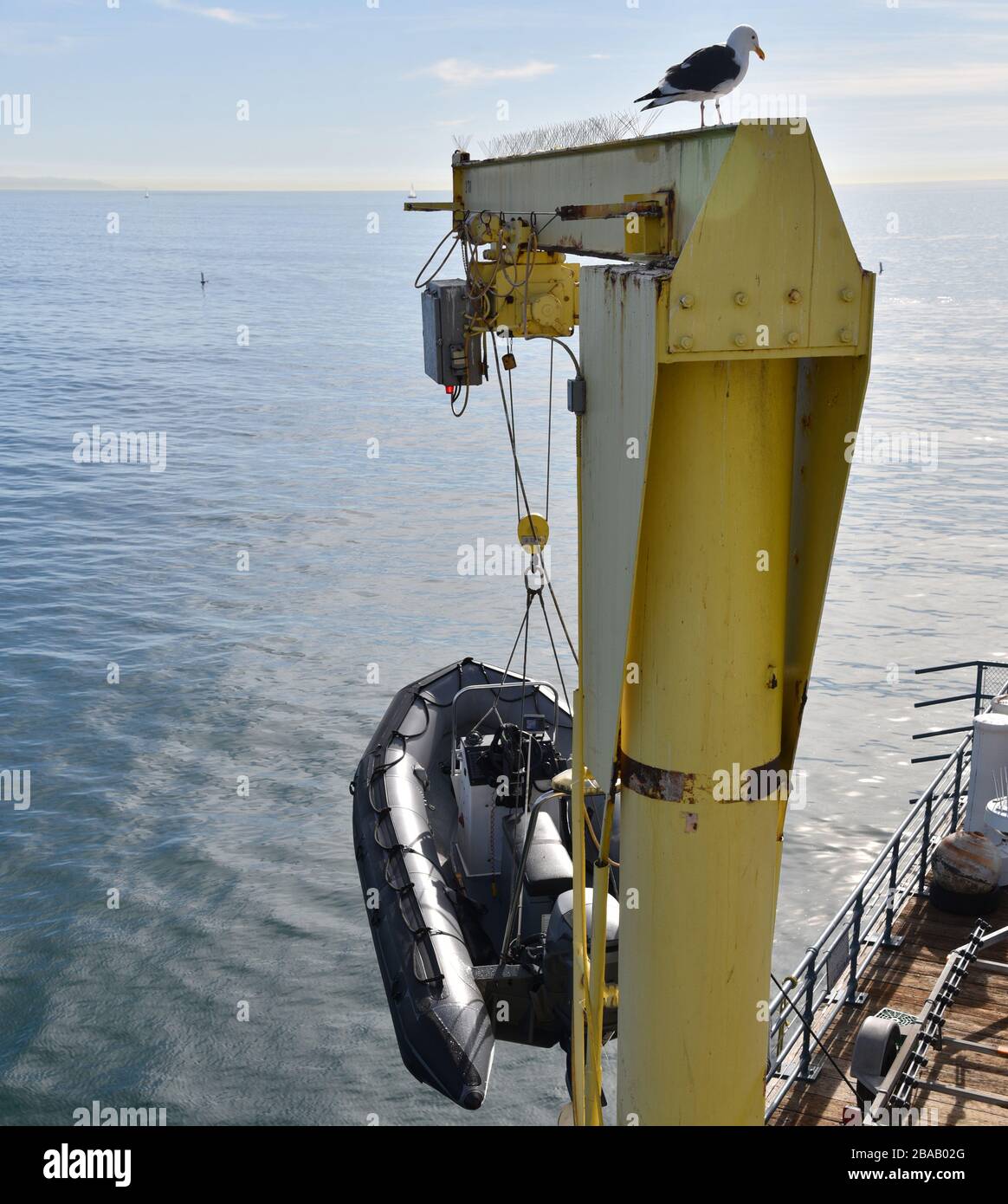 A dinghy boat being hoisted onto a dock by a crane Stock Photo - Alamy