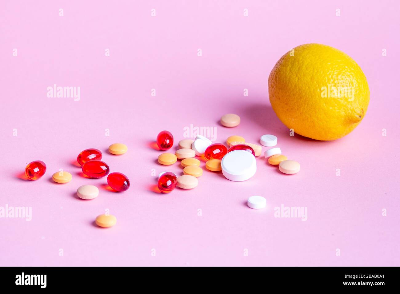 Lemon and scattered multi-colored pills on a pink background Stock ...