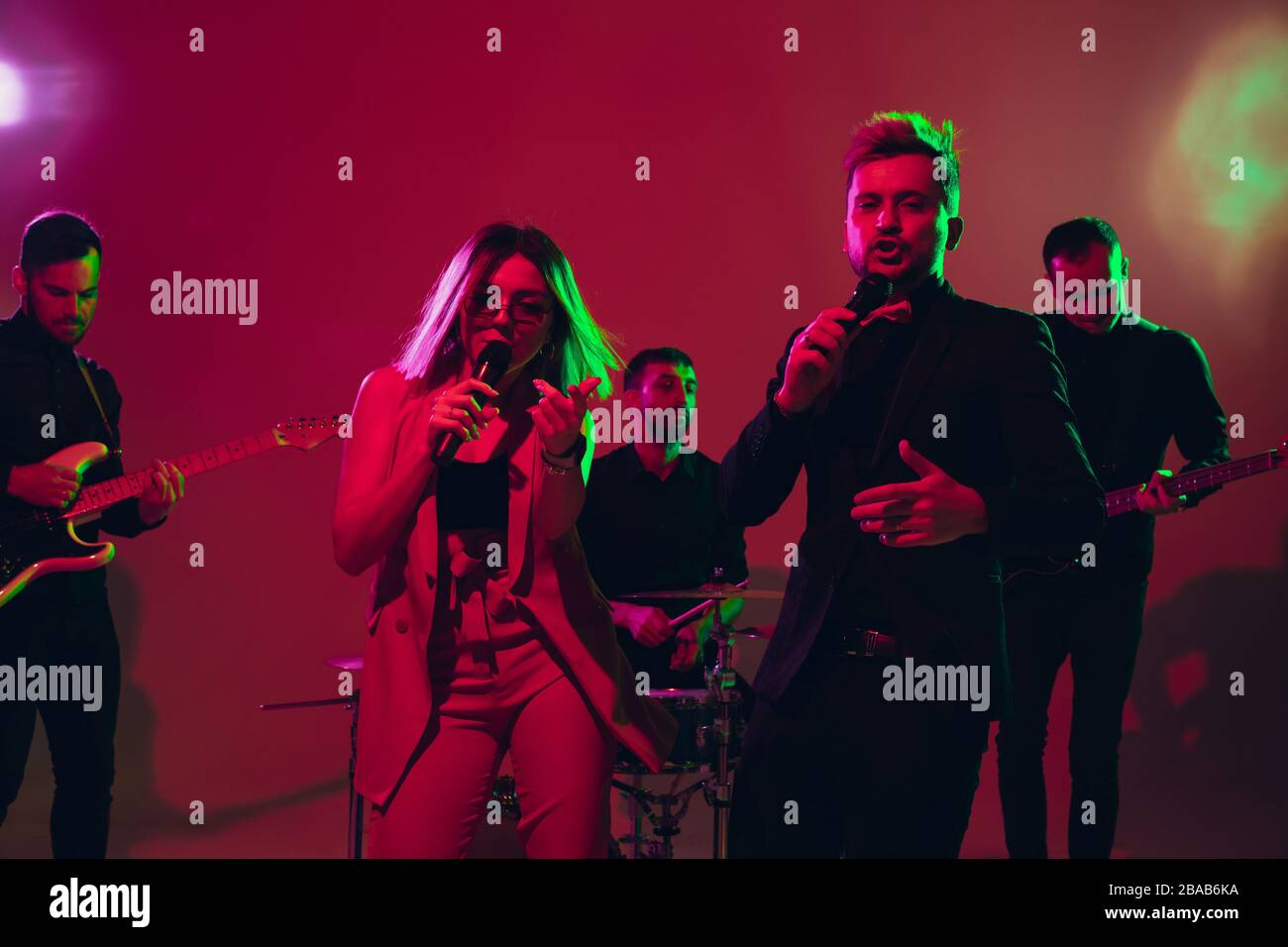 Young and joyful caucasian musicians performing on red studio ...