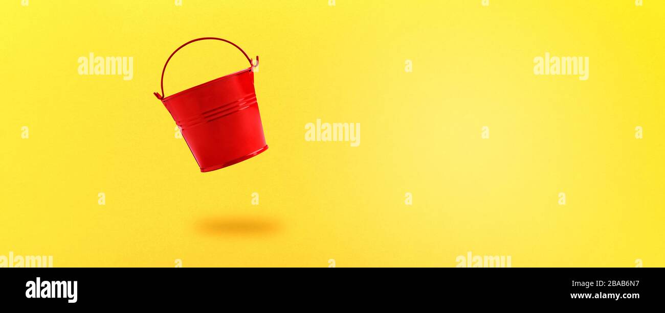 levitating red iron bucket, image on yellow background, panoramic mock ...