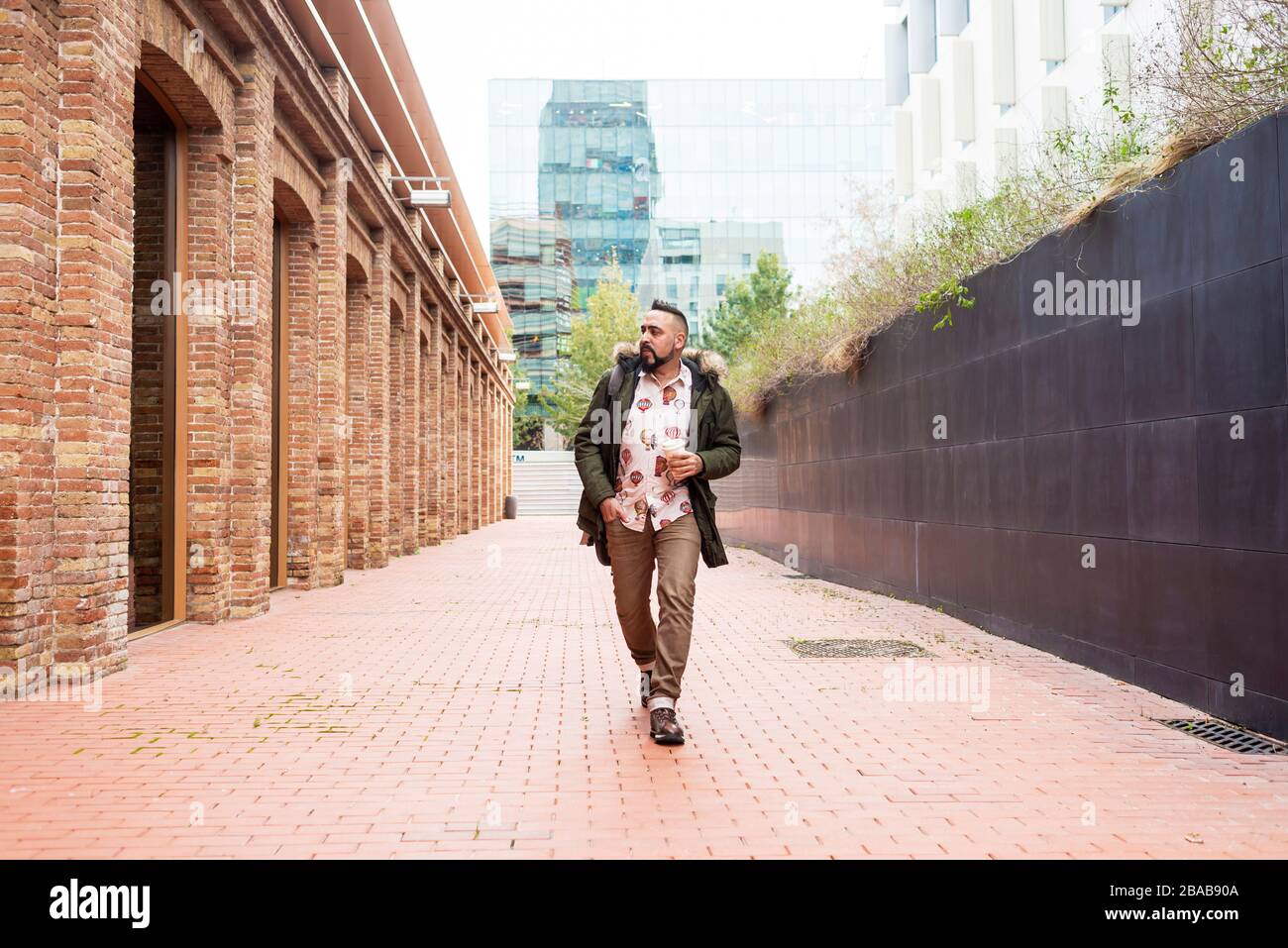Bearded man walking across pathway holding a take away coffee Stock ...