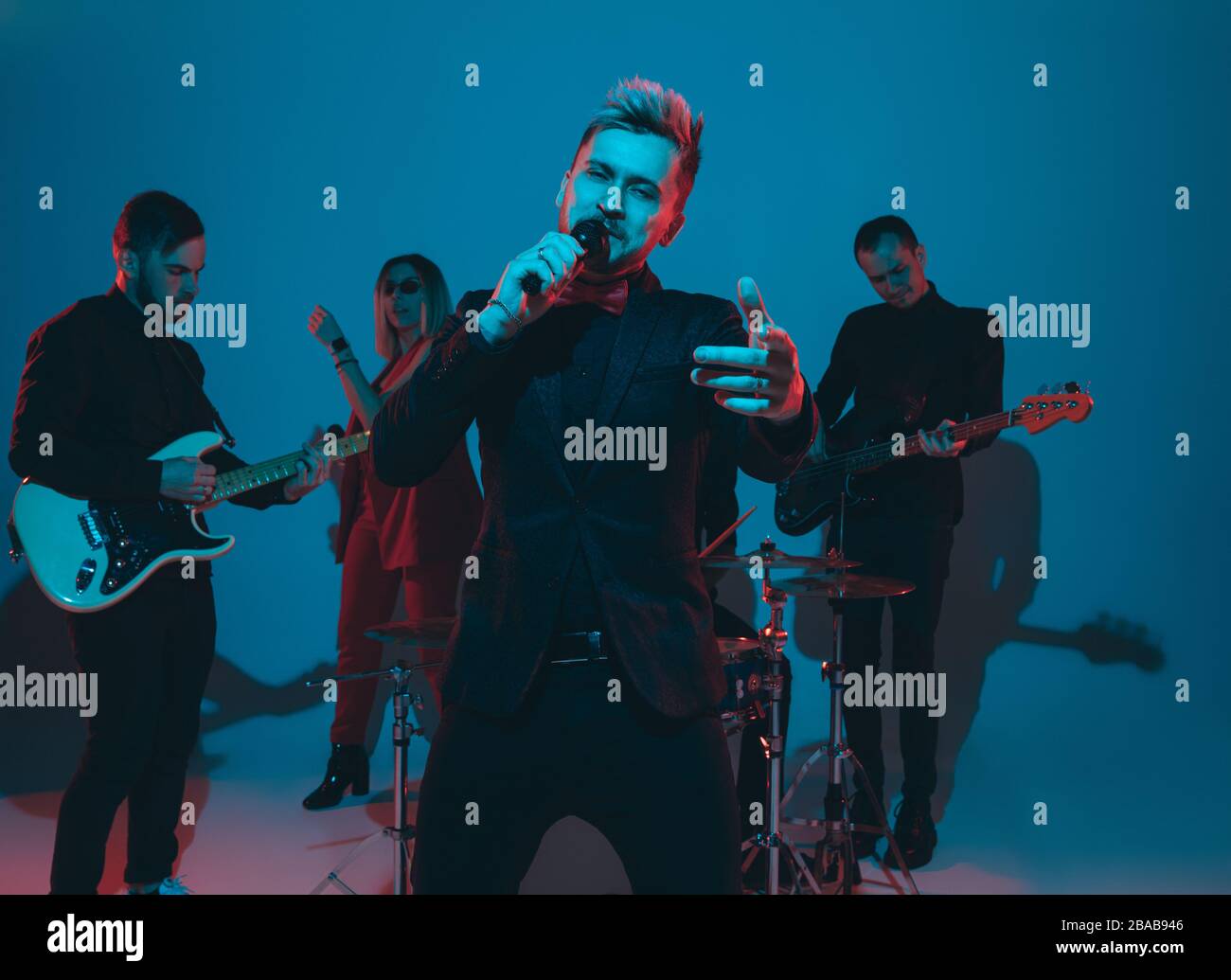 Young caucasian musicians, band performing on blue studio background in ...