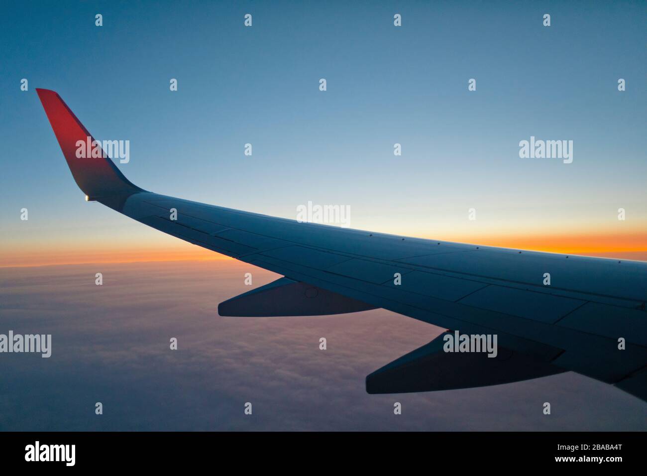 Wing of a plane mid air at sunset flying over planet earth Stock Photo ...