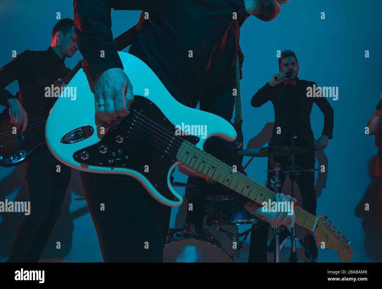 Young caucasian musicians, band performing on blue studio background in ...