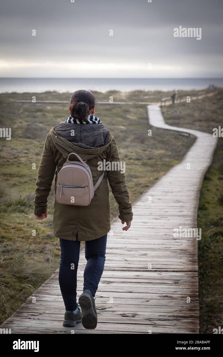 Vertical photo of a woman walking along a wooden walkway Stock Photo ...
