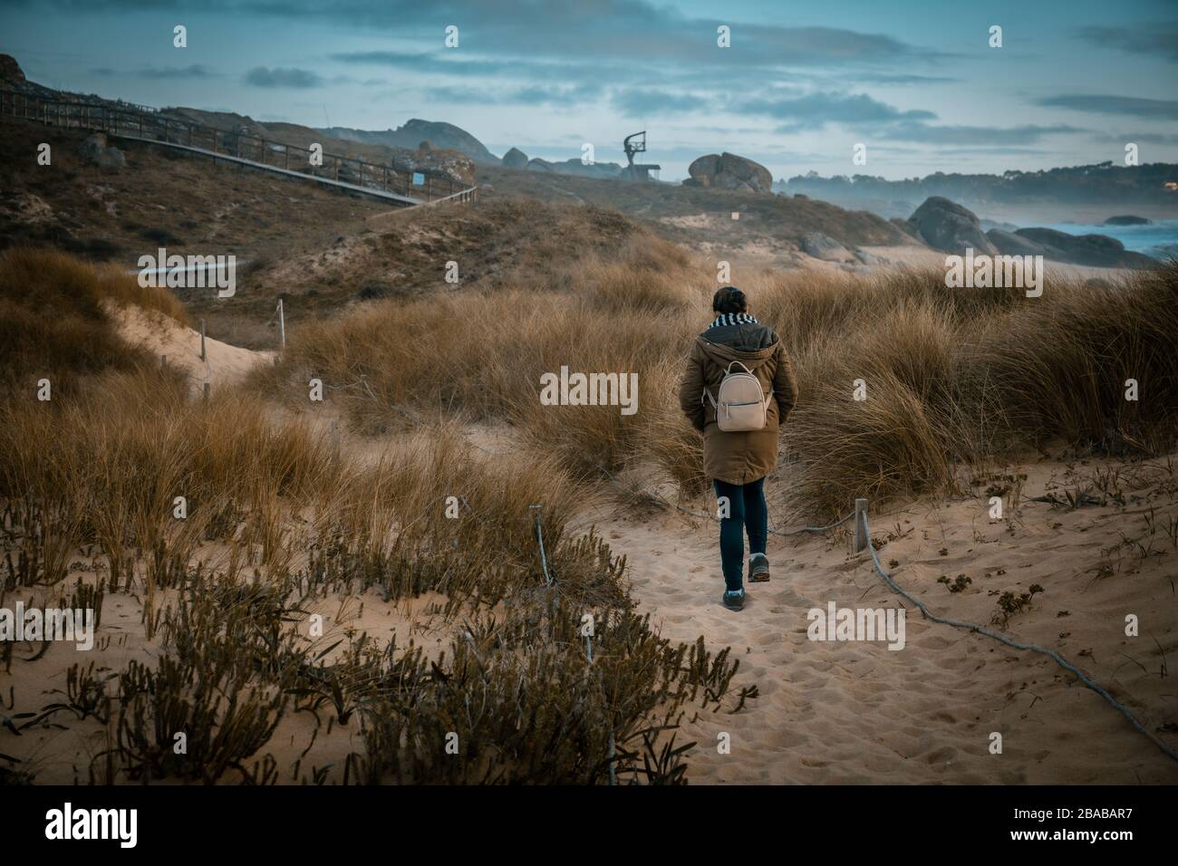 Woman walking through a beautiful dune area on the coast Stock Photo ...