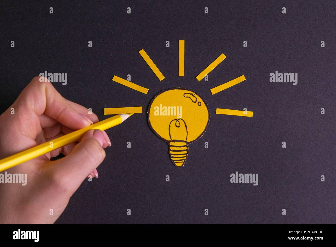 A yellow pencil in hand next to a creative painted light bulb. The ...