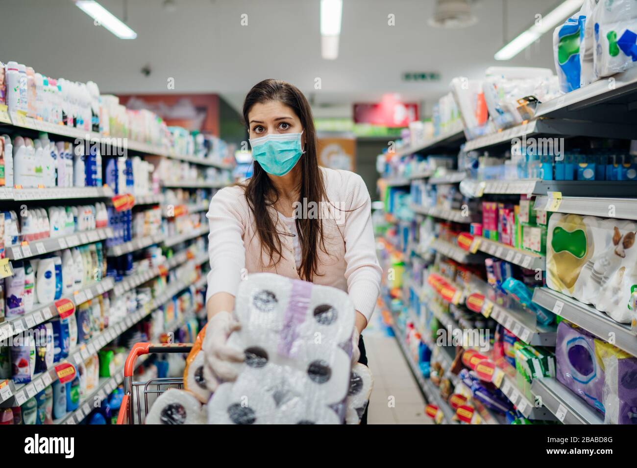 Woman shopper with mask and gloves panic buying and hoarding toilette ...