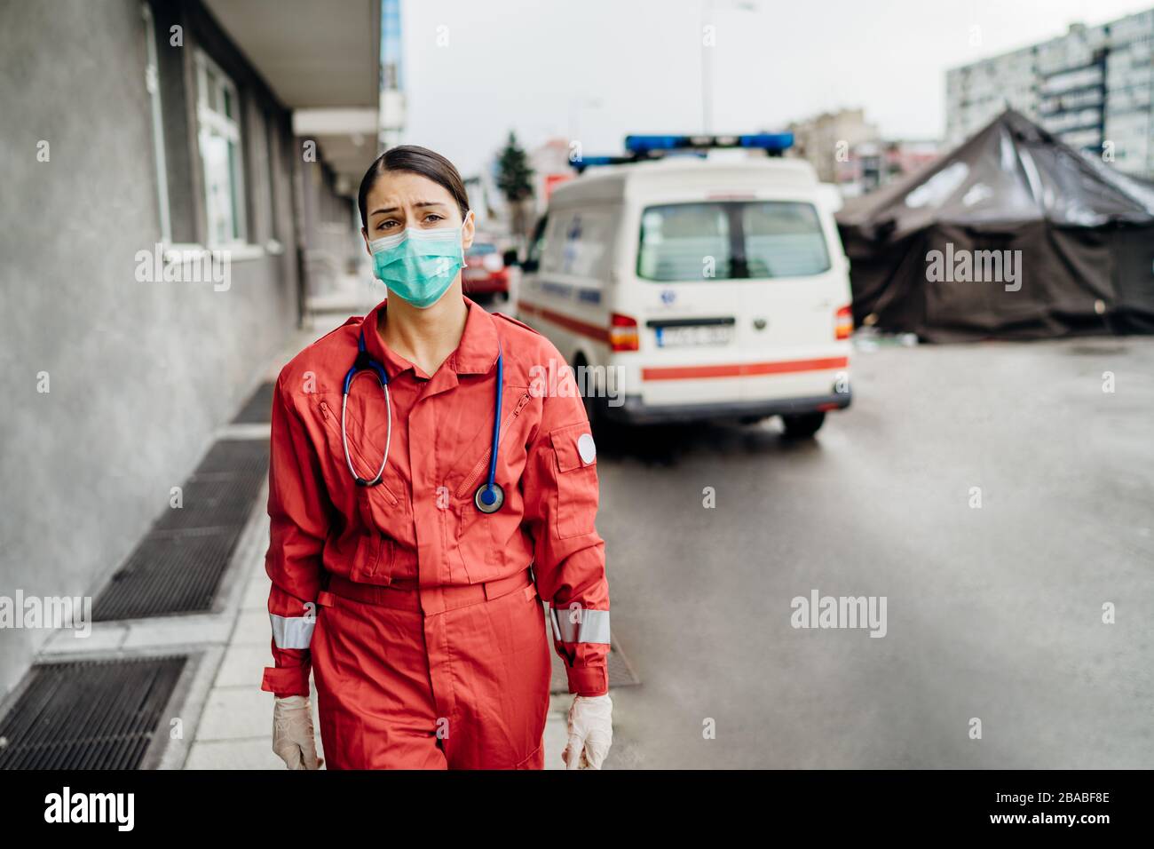 Crying paramedic in front of isolation hospital facility.Mental melt ...