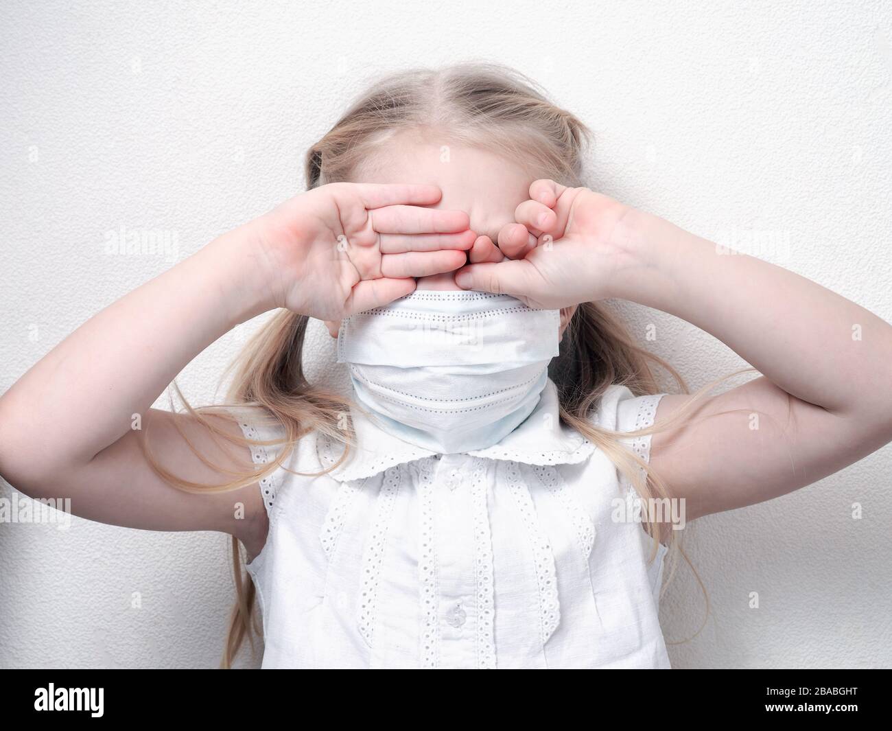 a child in a medical mask covered his face with his hands Stock Photo ...