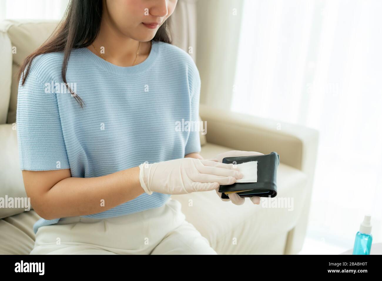 Asian woman is spraying alcohol, disinfectant spray on money wallet ...