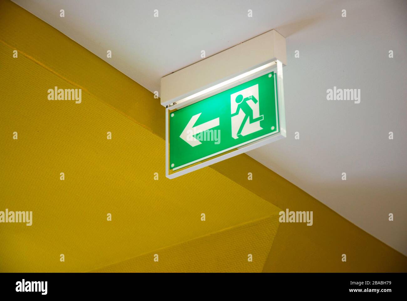 Emergency exit sign with light in a room with yellow walls Stock Photo ...