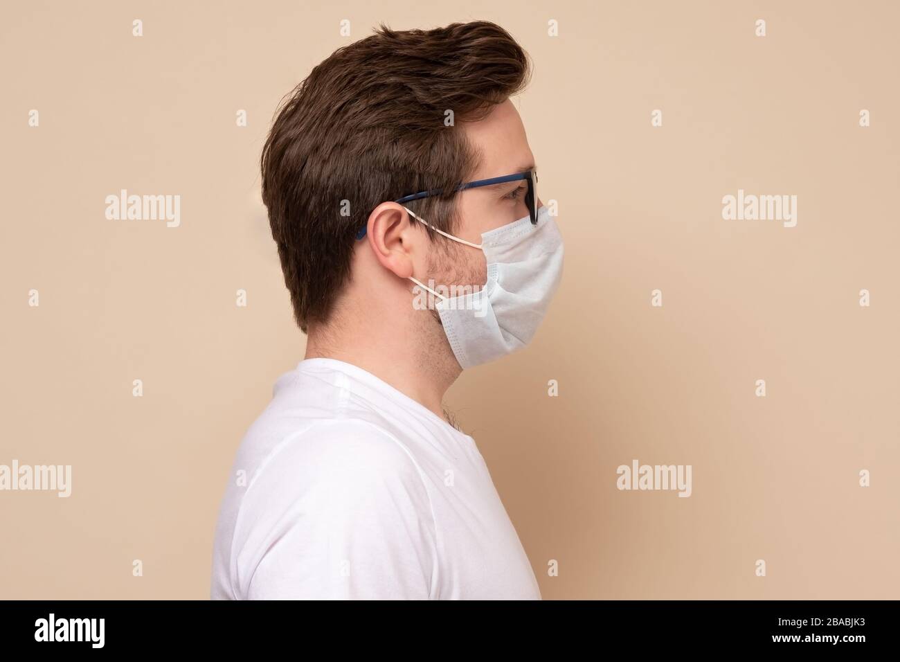 Side view of caucasian young man with single use medical mask to ...
