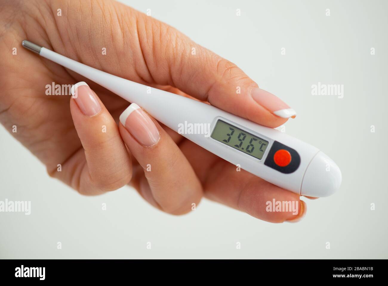 A hand holds a thermometer. Fever as a sign of Coronovirus Covid-19 ...