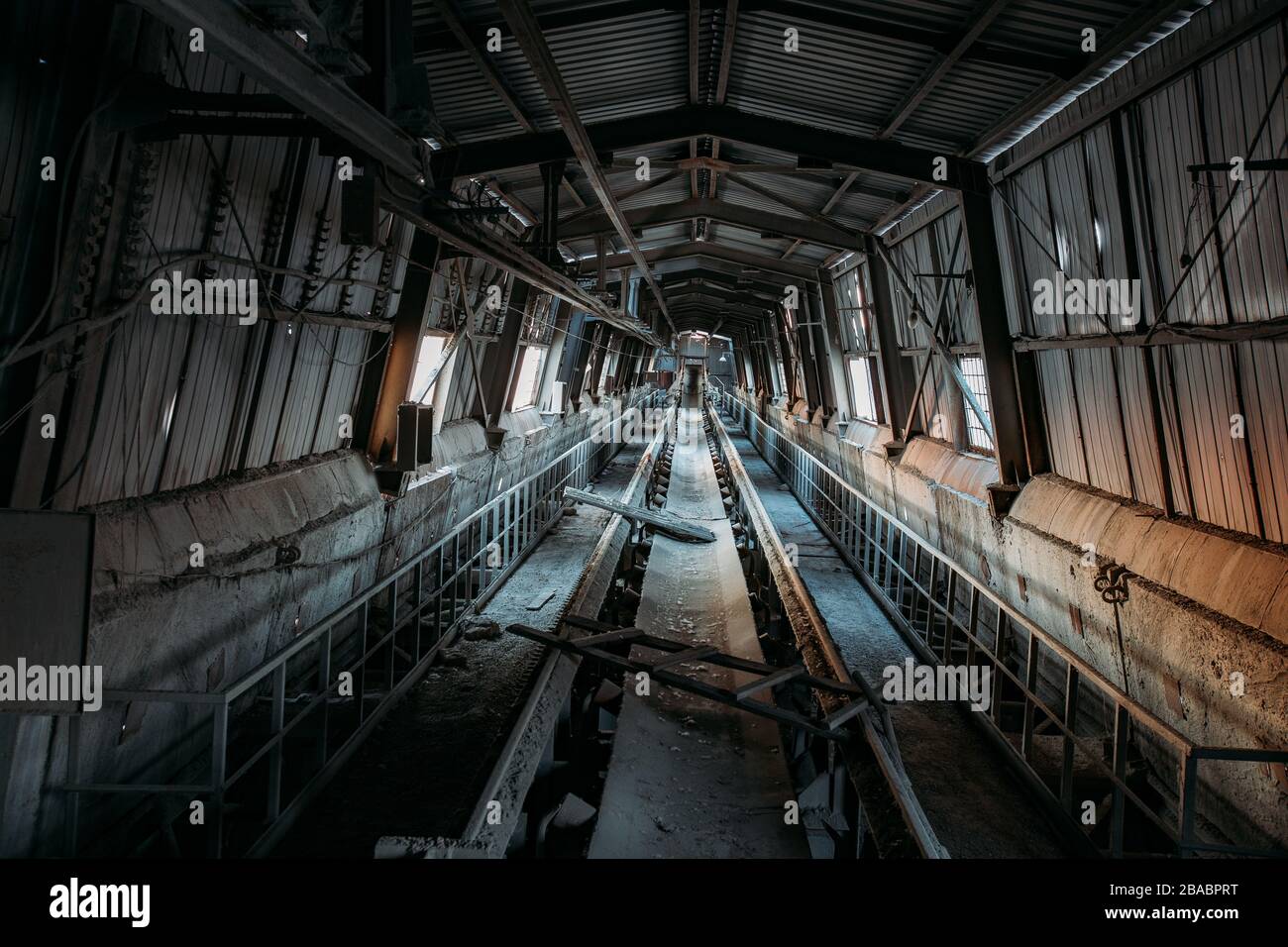 Abandoned cement and concrete factory. Old rusty conveyor in corridor ...