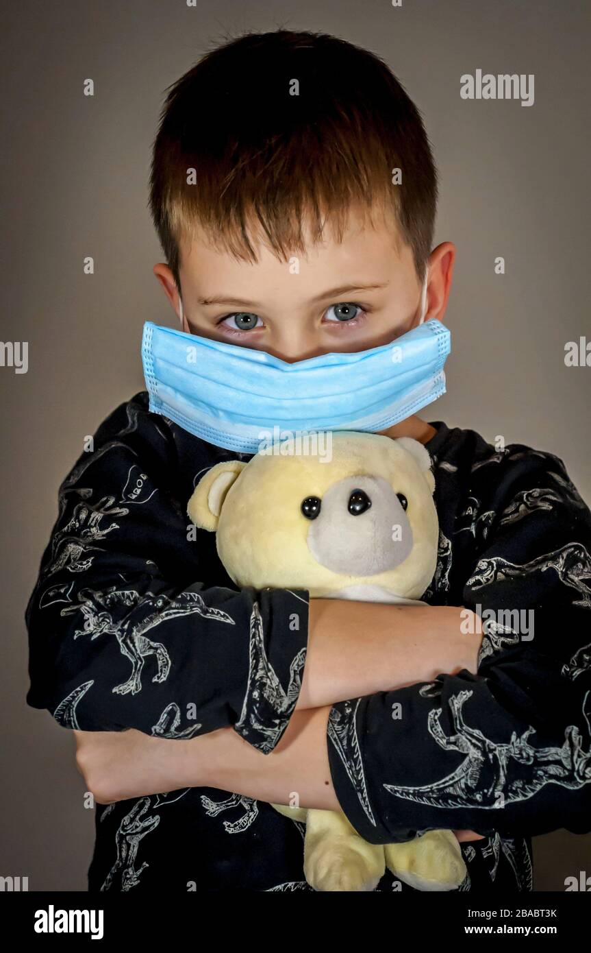 Sad and tense cute Caucasian boy wearing a protection mask holding a ...