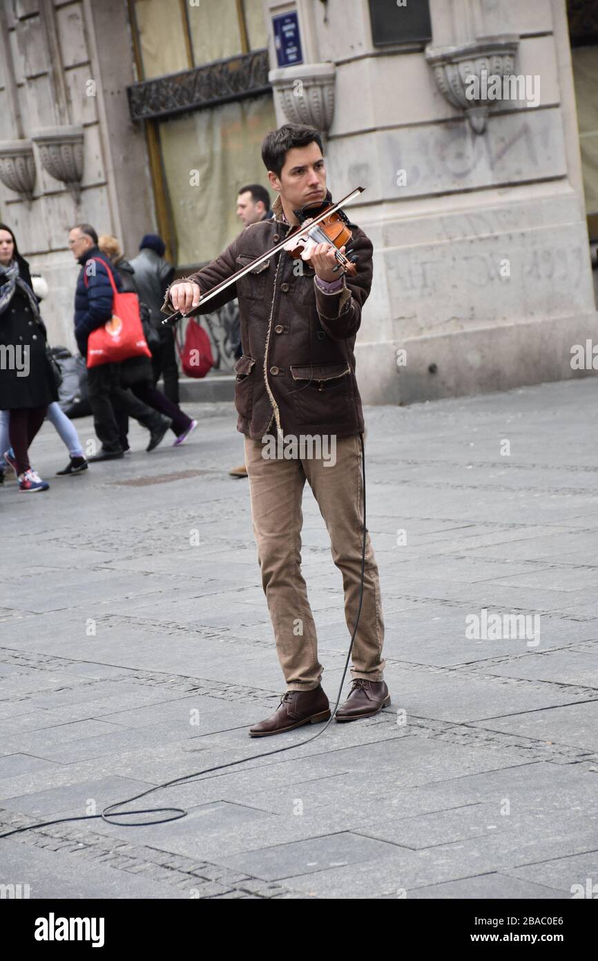 City street atmosphere with street violin player Stock Photo - Alamy