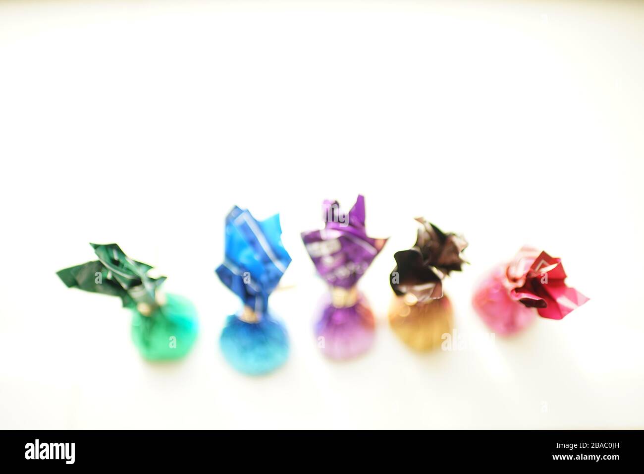 Blurred chocolate candies in colorful wrappers, top view, selective ...