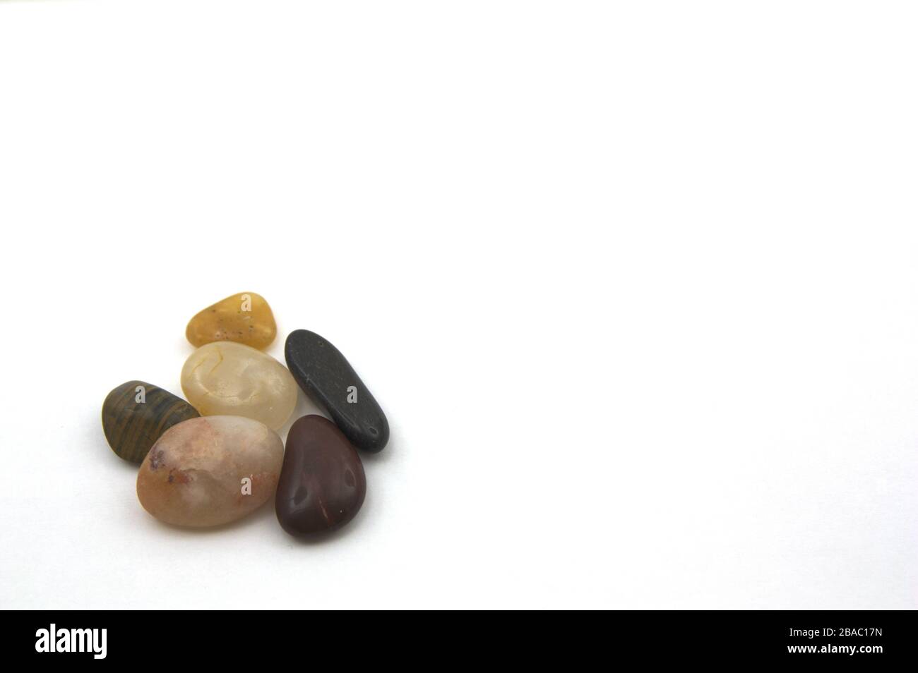 Image of some dark colored river rocks on a white background, with ...
