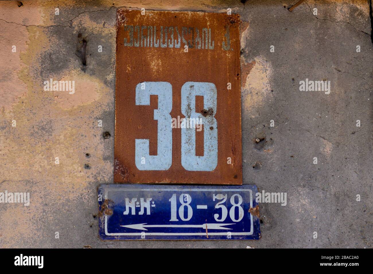 Street number 36 on a metal placard against a stucco wall, white ...