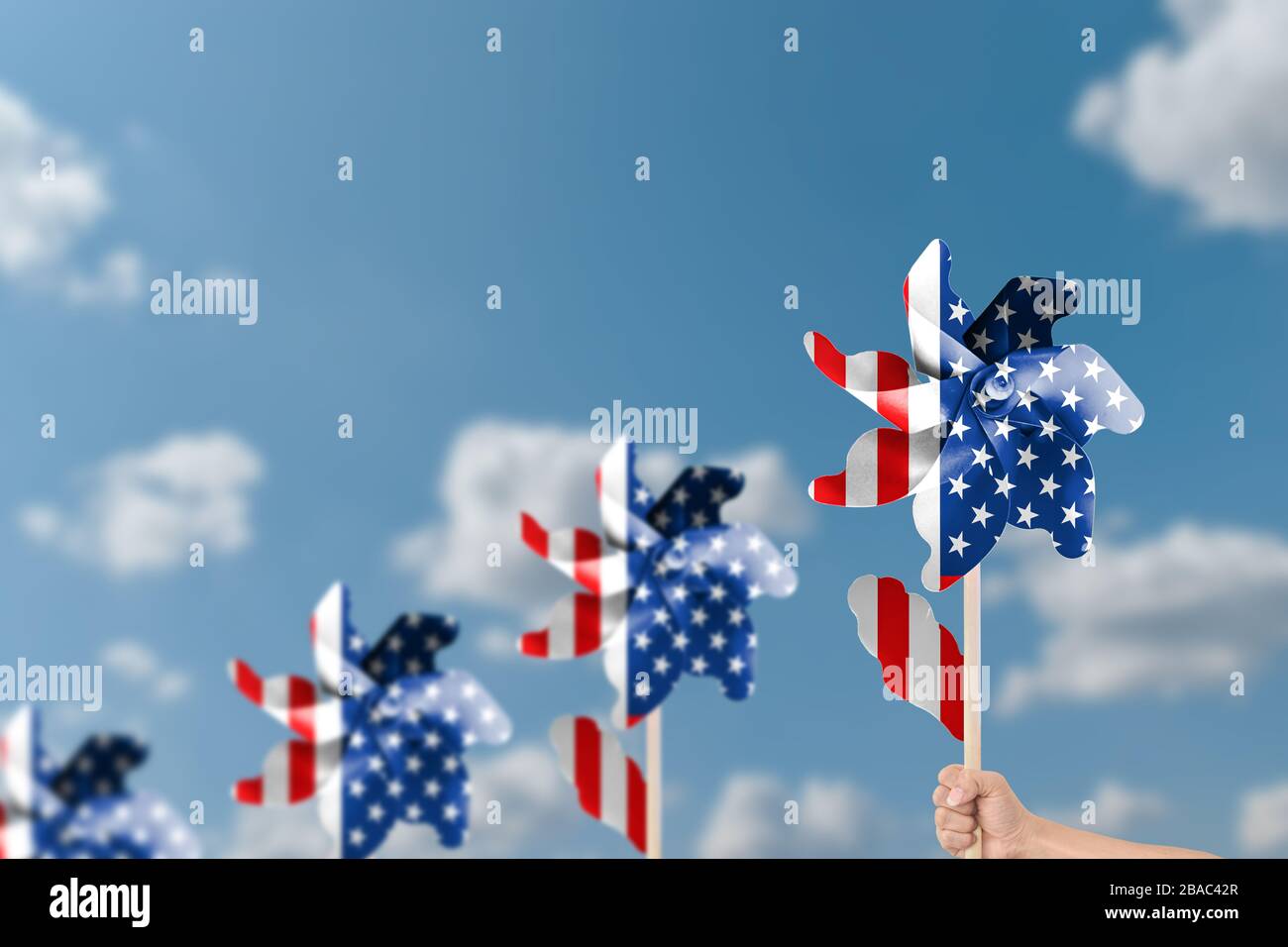 Hand holding wind turbine patriotic of USA over blue sky background ...