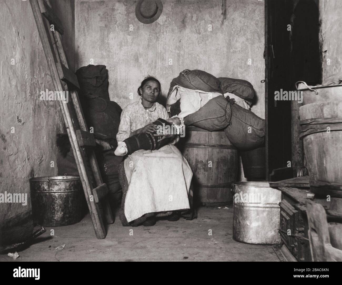 Italian immigrant rag-picker sits with her baby in a small run-down ...