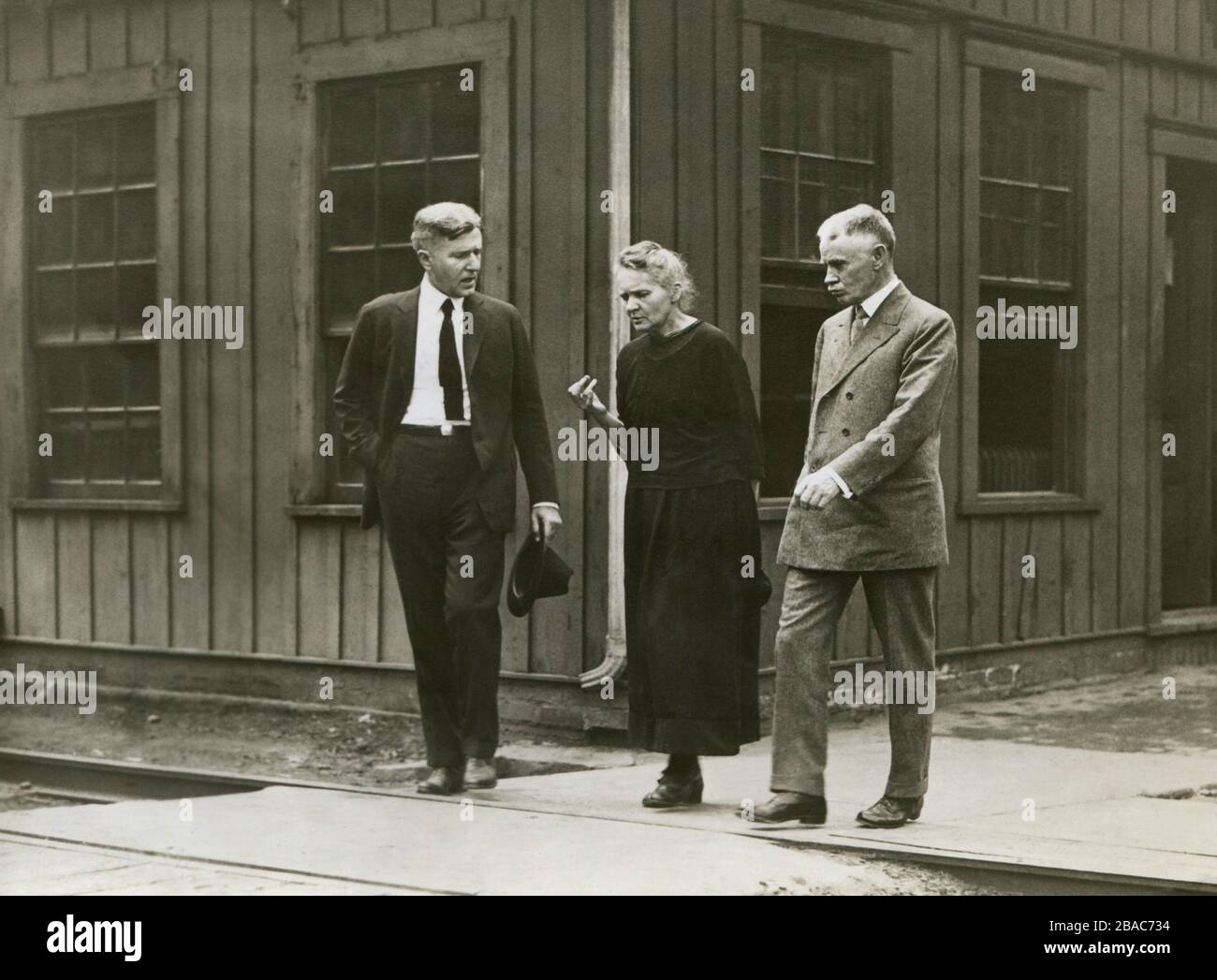 Marie Curie walking with fellow scientists at radium refinery plant in ...