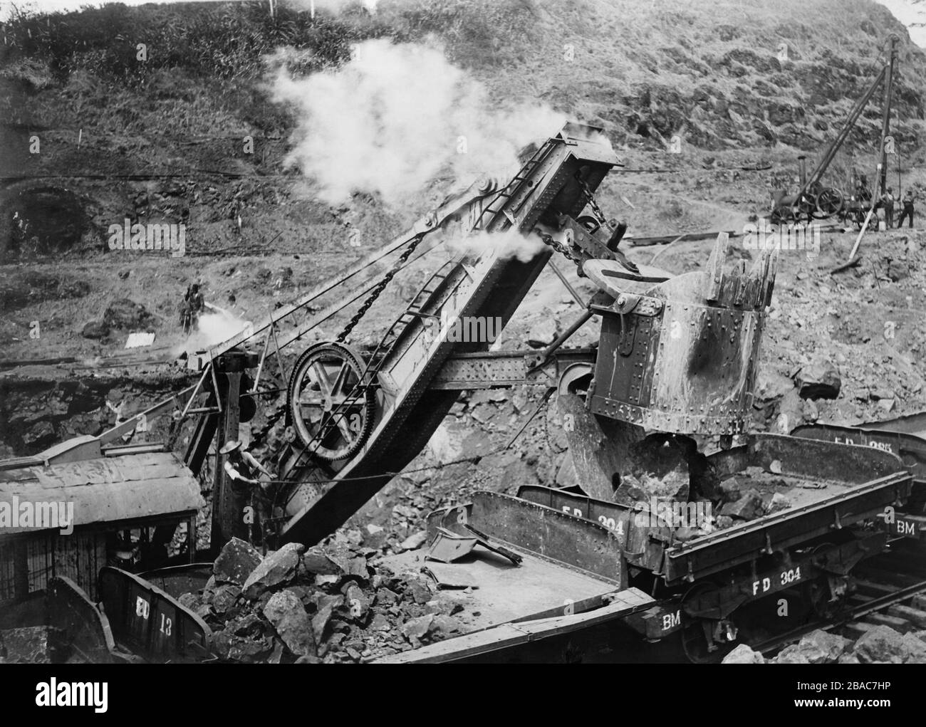 Business end of 95 ton steam shovel loading boulders onto train cars at ...