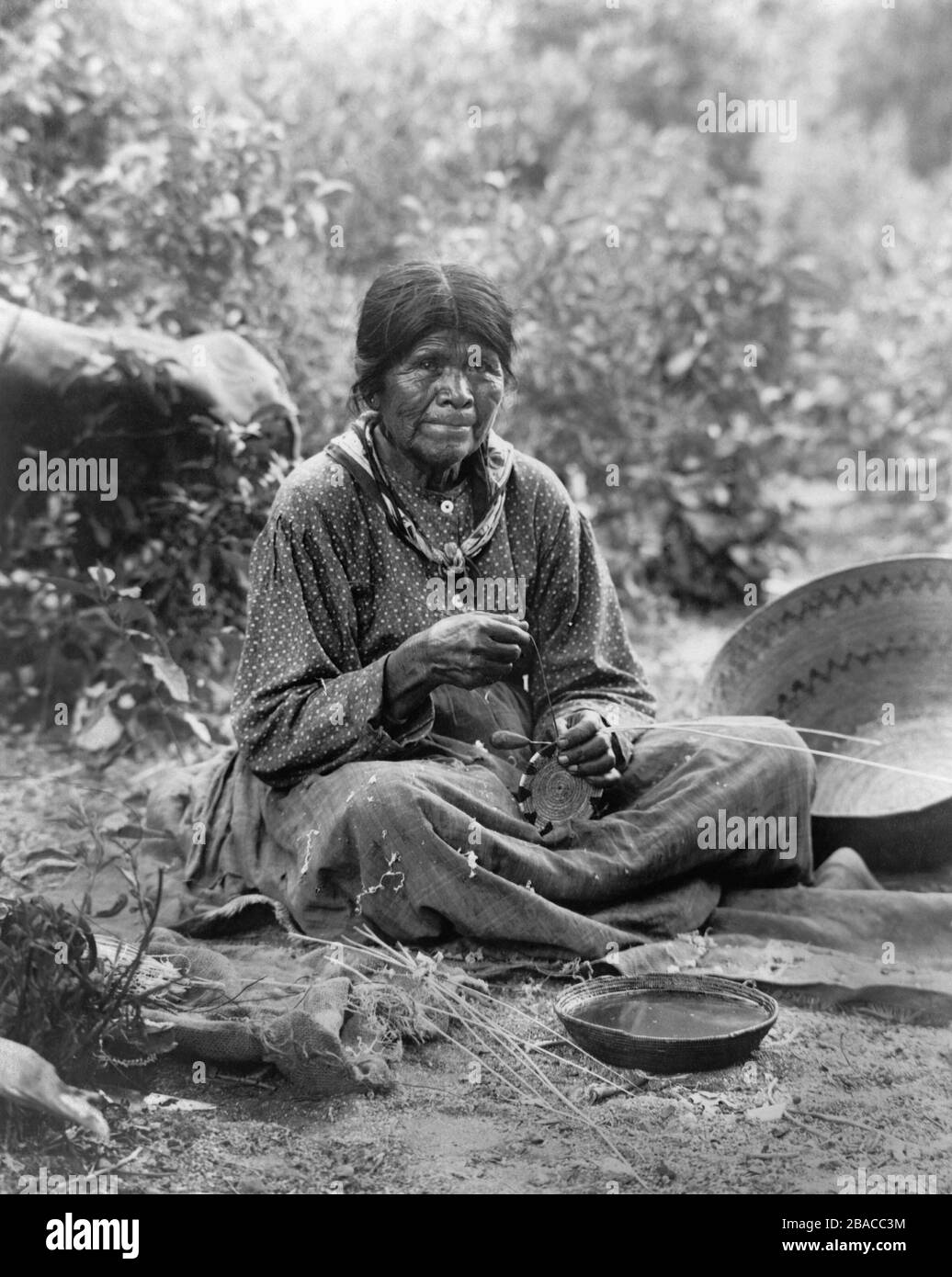 A Paiute woman weaves a basket. In their Great Basic semi-arid ...