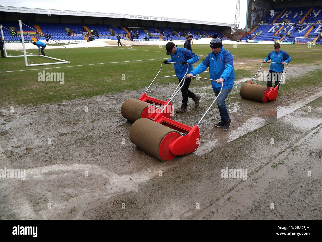 Ground staff members push water off the pitch ahead of the match Stock ...