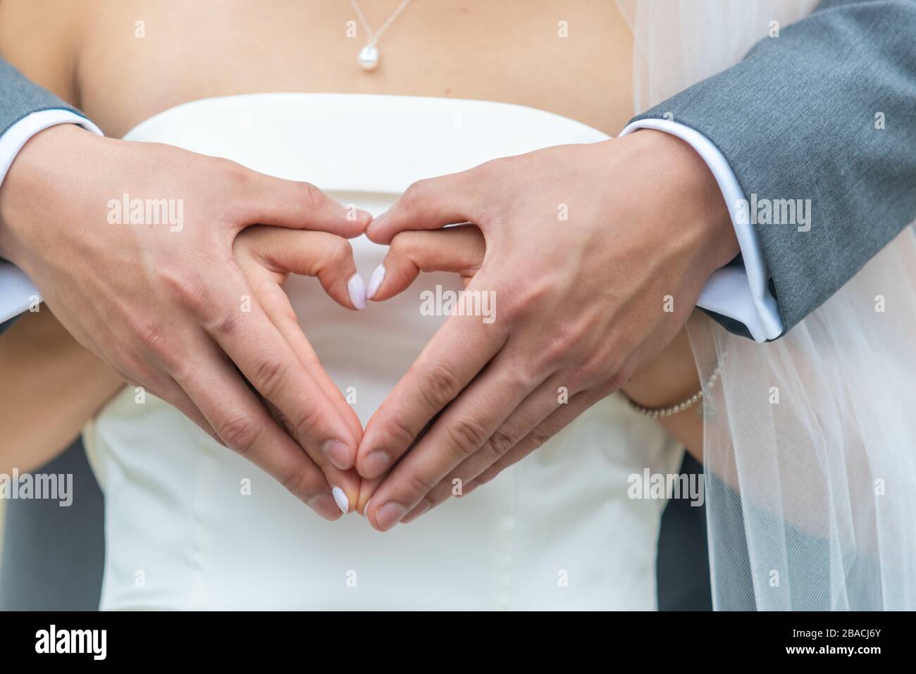 Romantic bride and groom showing a heart symbol with hands Stock Photo ...