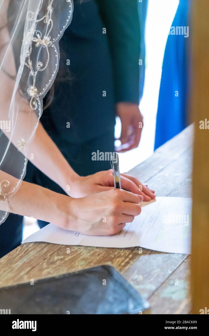 Bride and a groom putting their signatures under the marriage ...