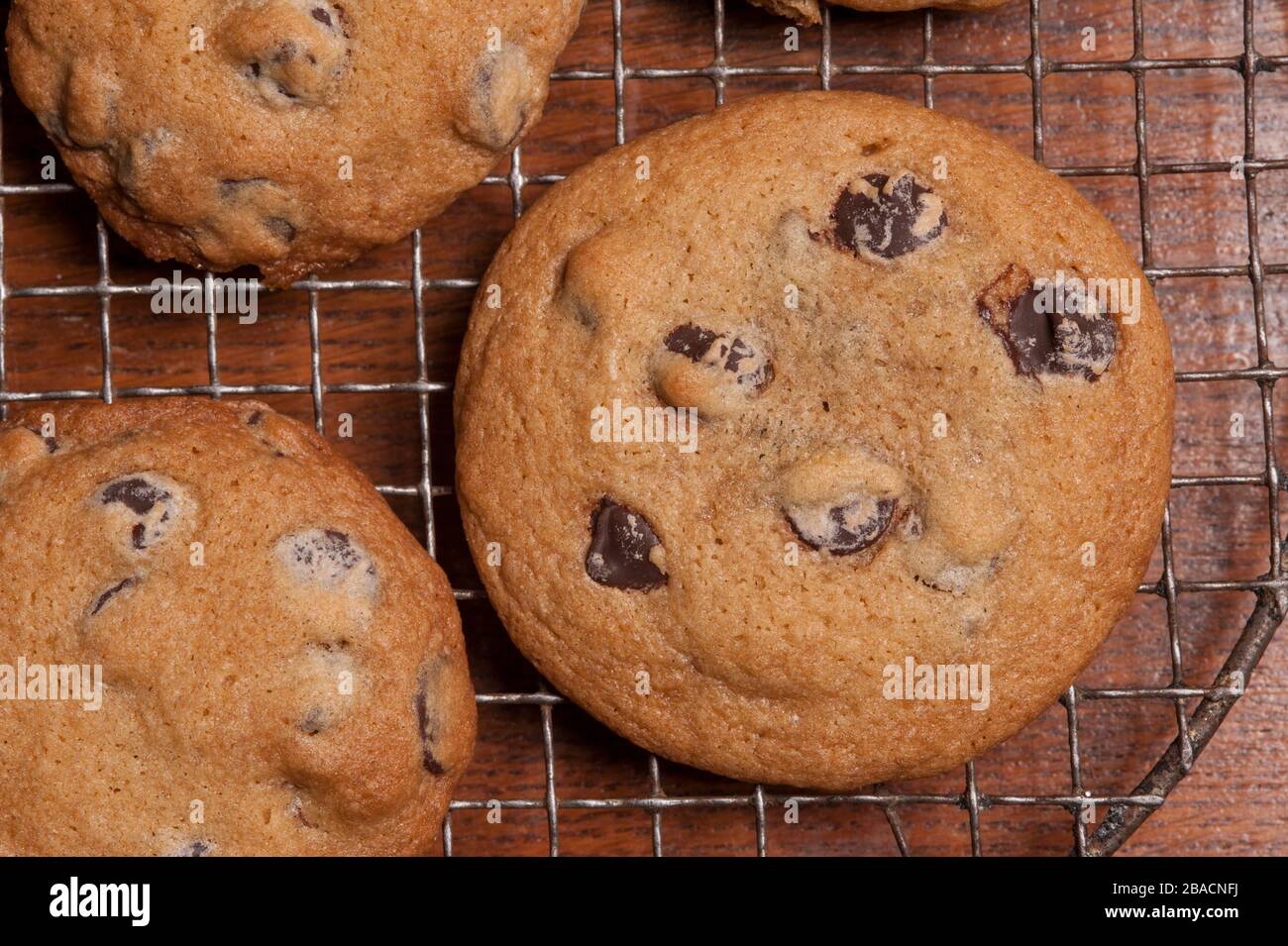 Looking down on chocolate chip cookies cooling on a wire rack on a wood ...