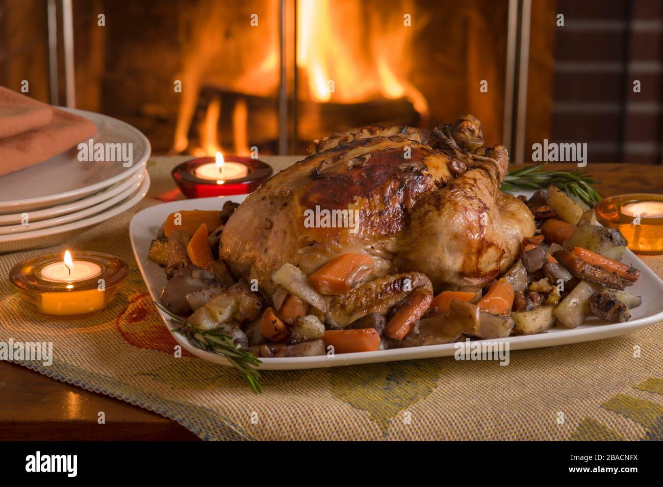 Platter of roasted chicken and vegetables on a table with plates ...