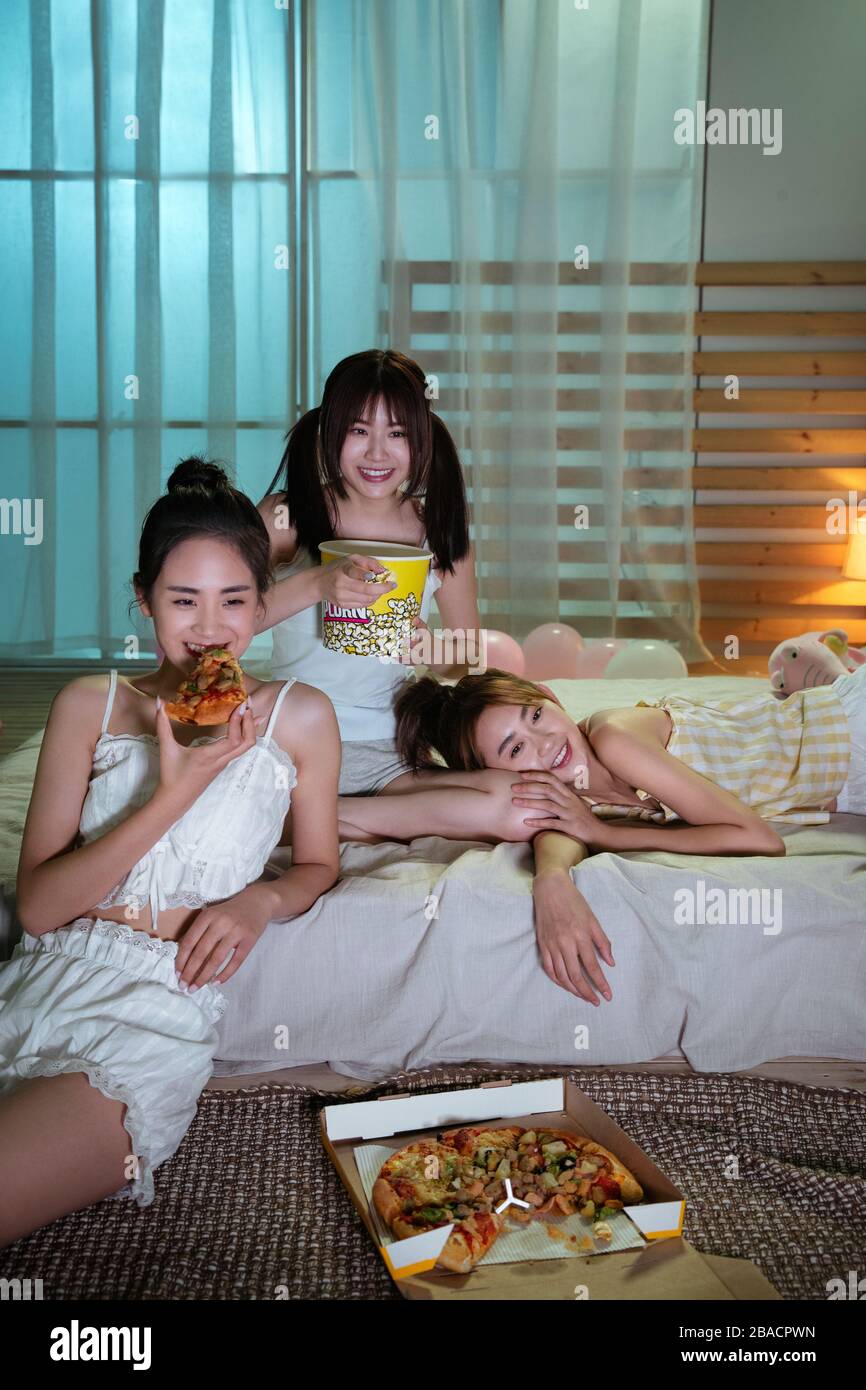 Girlfriends eating snacks, watching TV together Stock Photo - Alamy