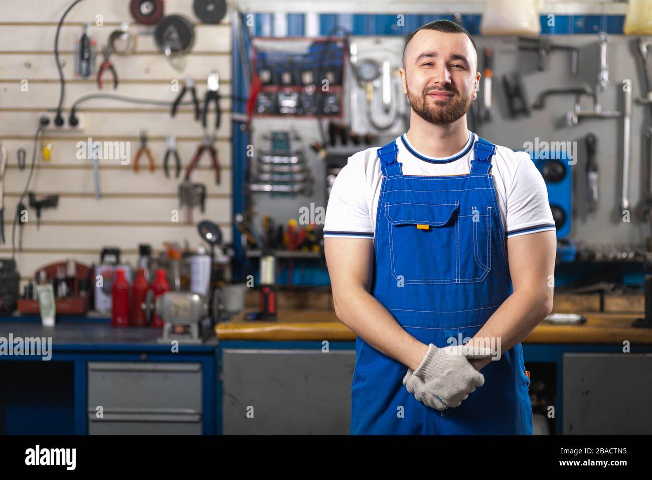 Handsome young man auto mechanic in special uniform clothes is standing ...