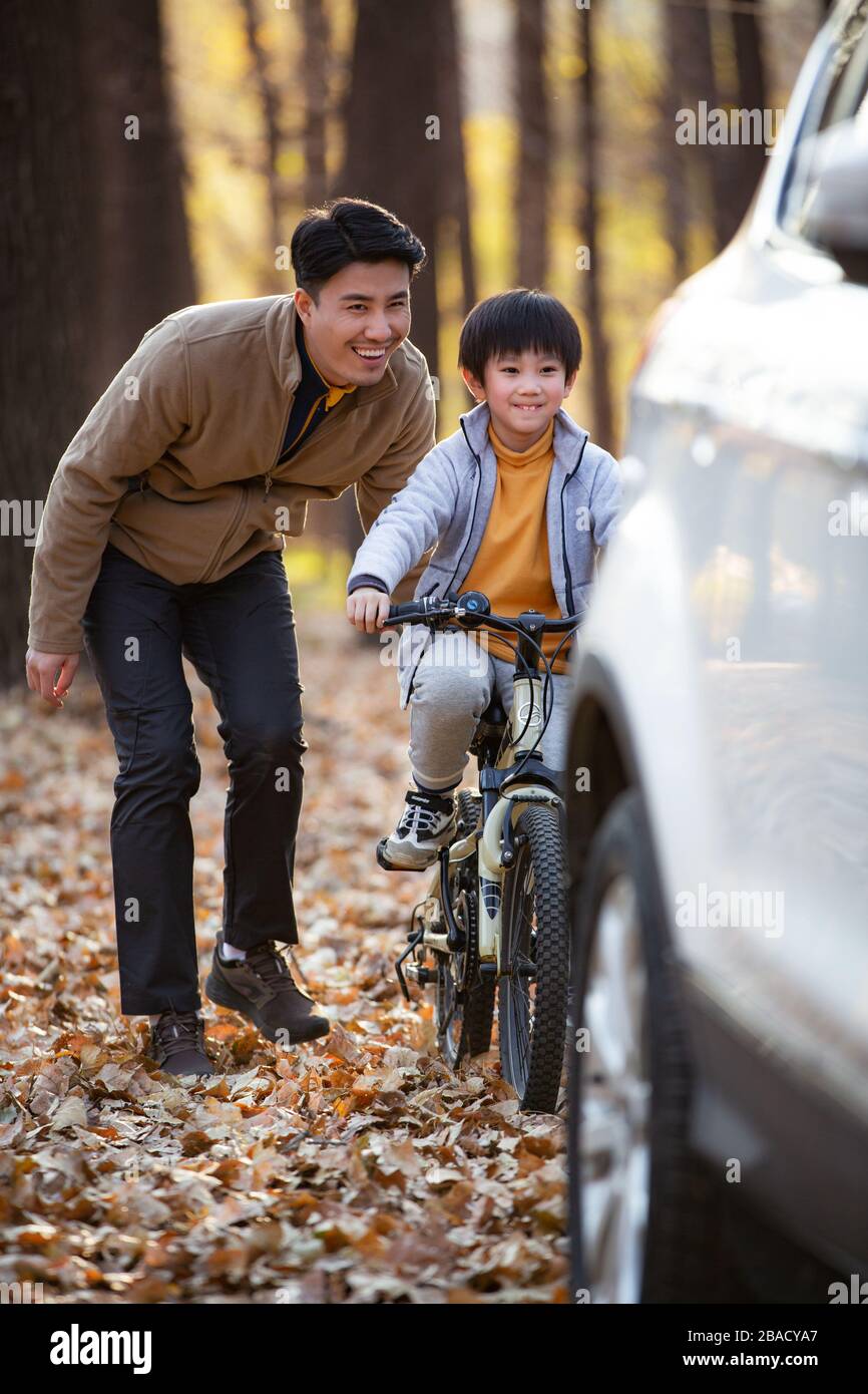 Happy father to protect his son to ride a bicycle Stock Photo - Alamy