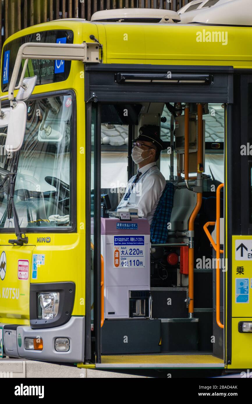 A yellow Nara city loop line bus waiting at a bus stop in Nara Park ...