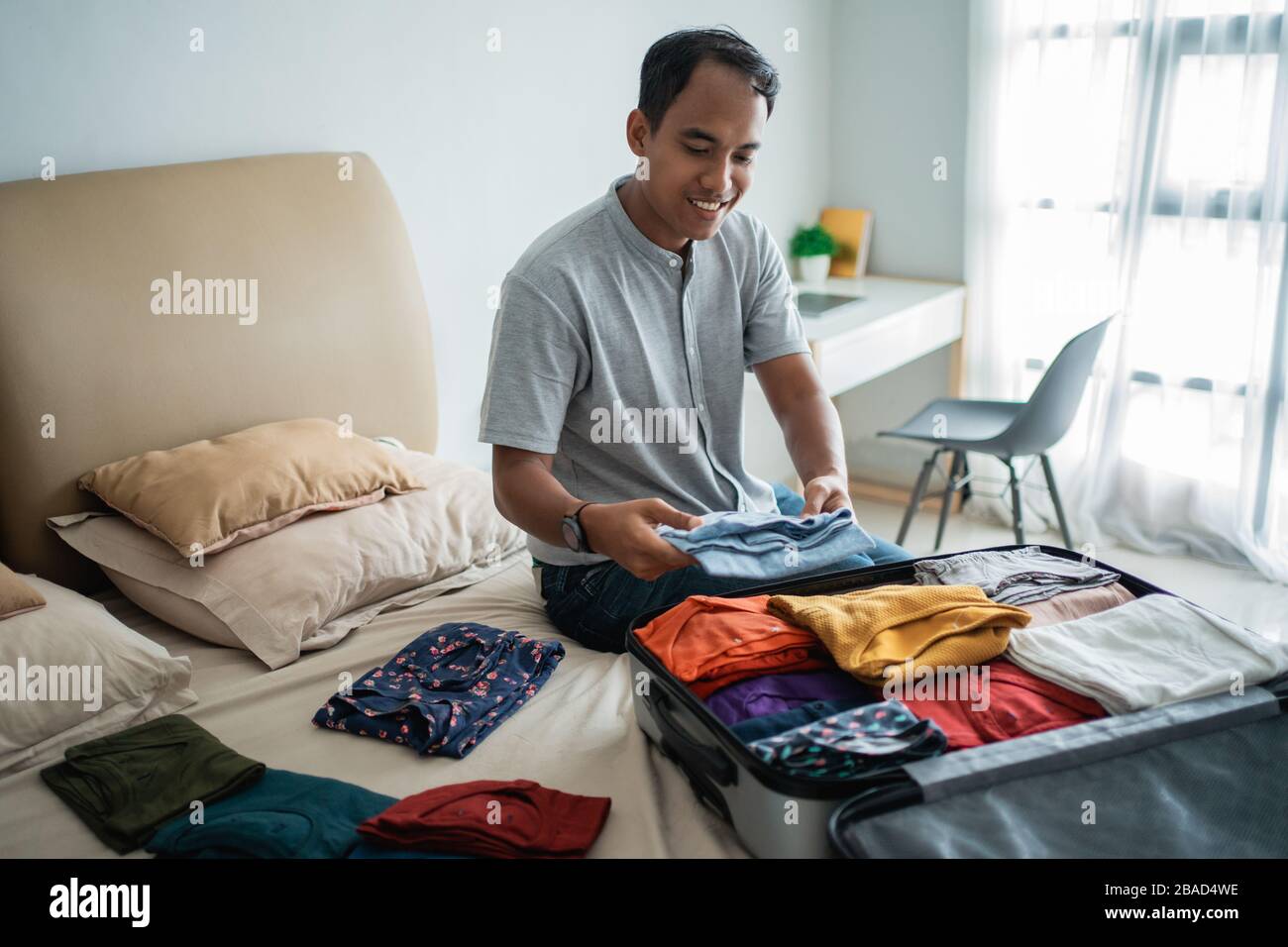 young man preparing his clothes put in the suitcase before go to long ...
