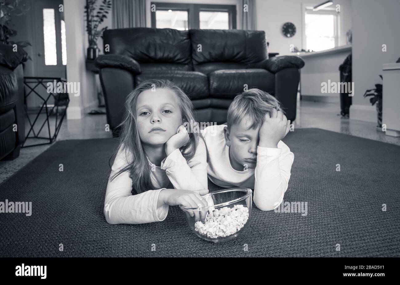 Coronavirus lockdow. Bored little girl and sad boy watching tv in ...