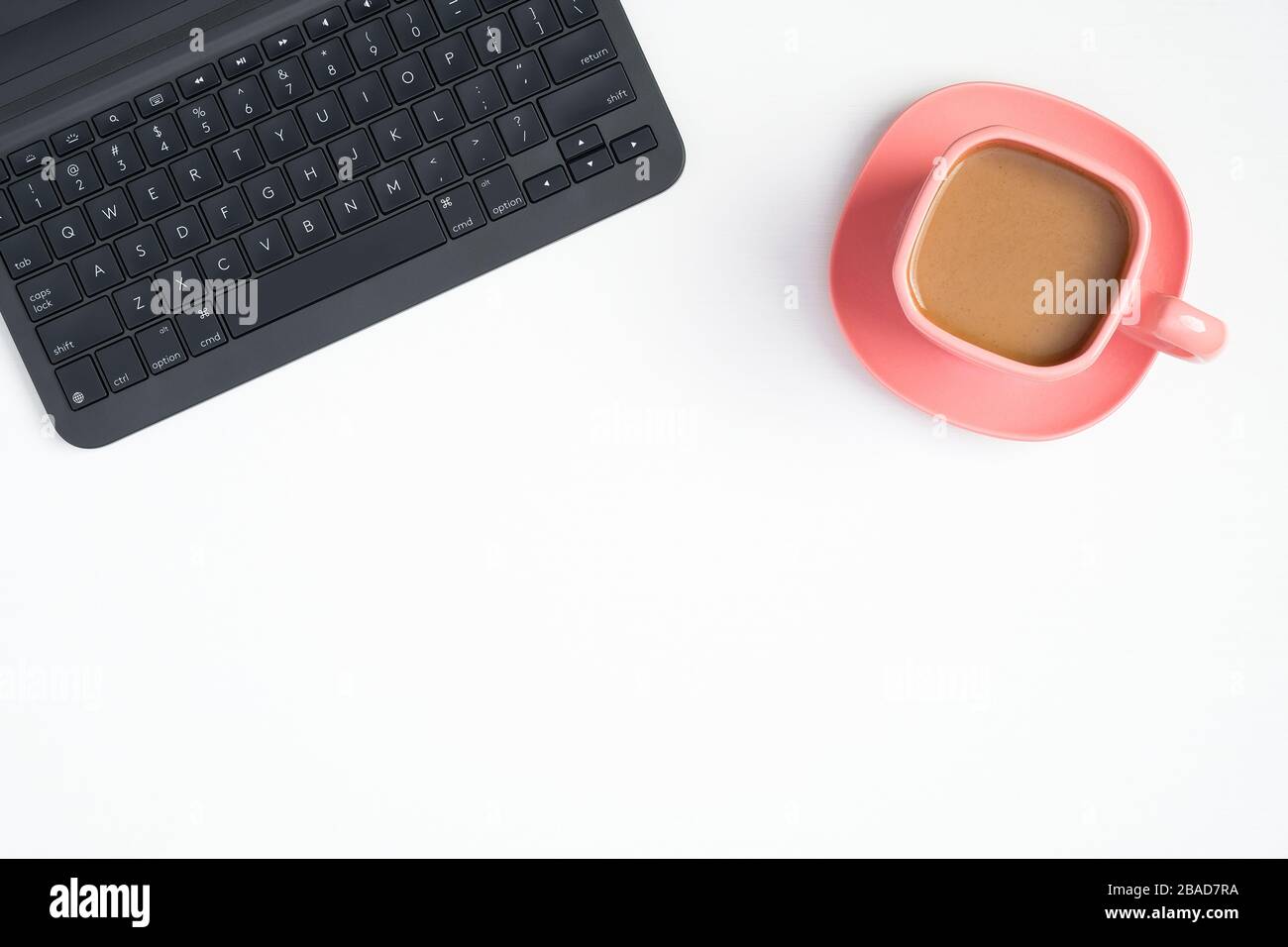 Laptop computer keyboard and pink coffee cup on white background ...