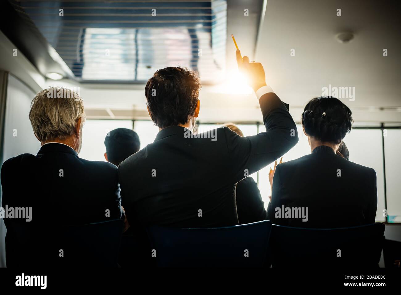 Business Audience raising hand up while businessman is speaking in ...