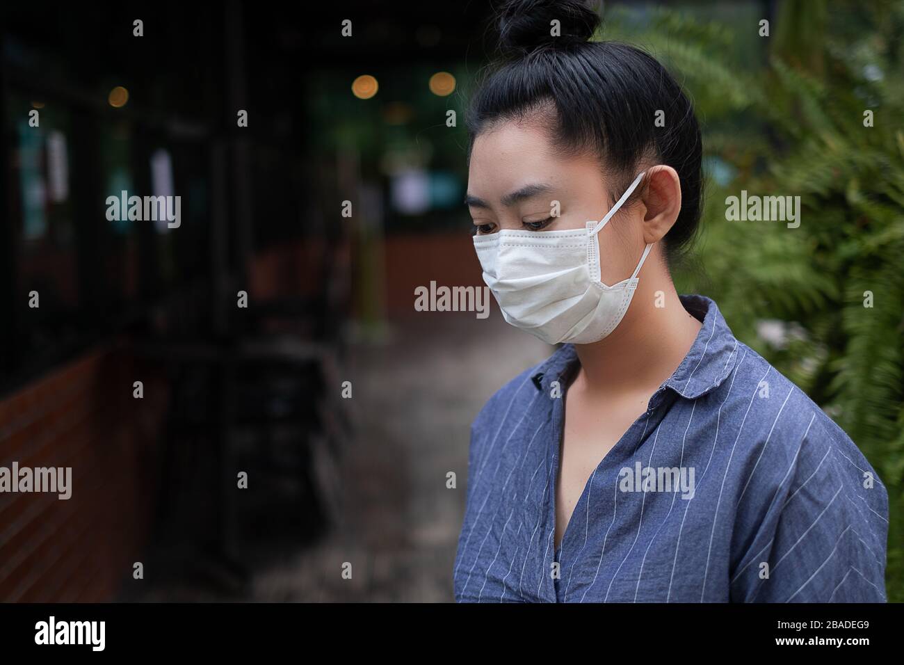 Close up of young Asia woman standing putting on a respirator N95 mask ...